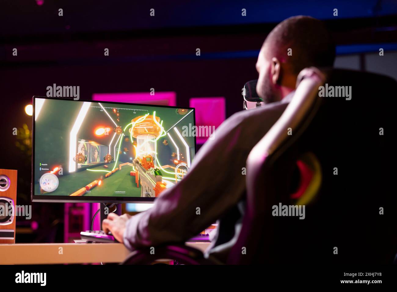 Man in neon lit apartment playing immersive video games on gaming PC at ...