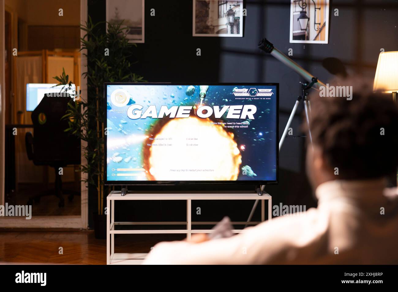Man playing videogames on smart TV display, receiving game over screen ...