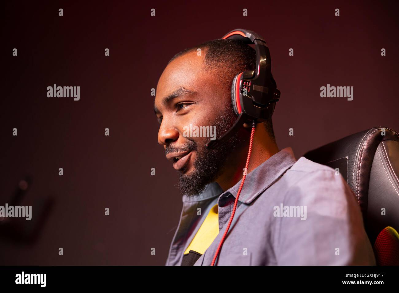 Joyful gamer with headphones on having fun in gaming room, playing ...