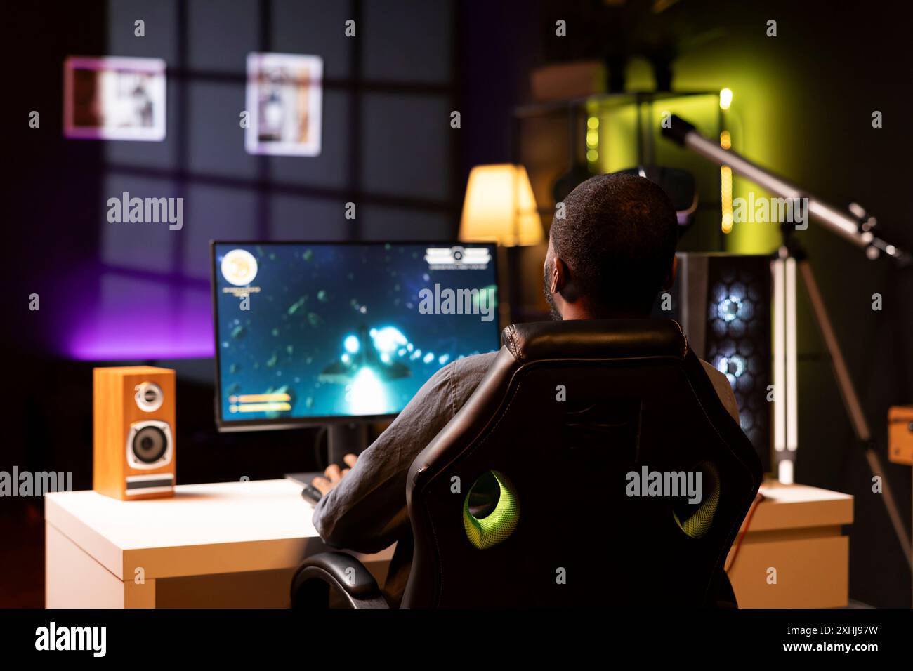 African american man playing SF space videogame on PC screen in neon ...