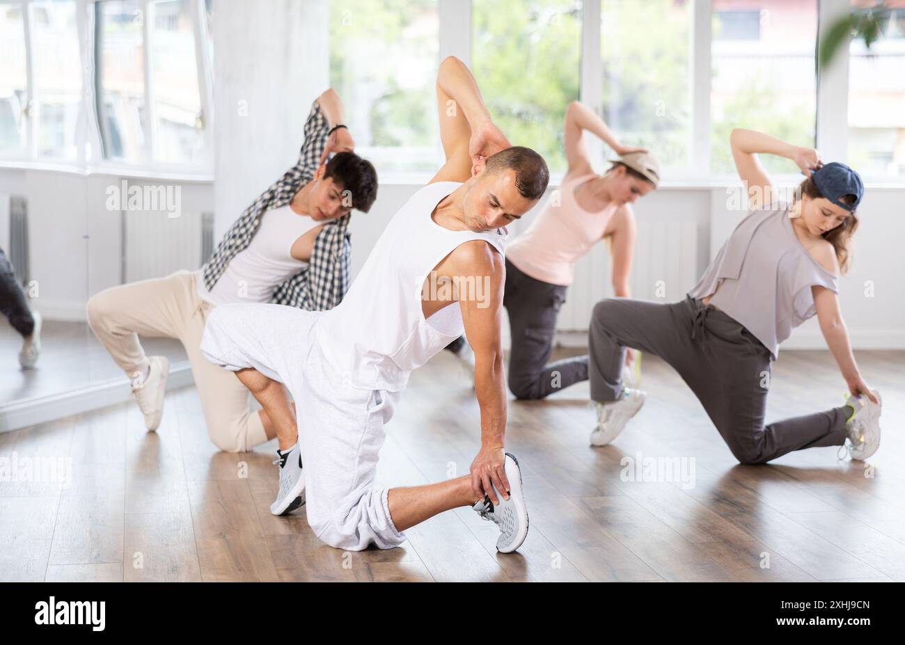 Man and his students perform hip hop dance on one bent leg, movement in ...