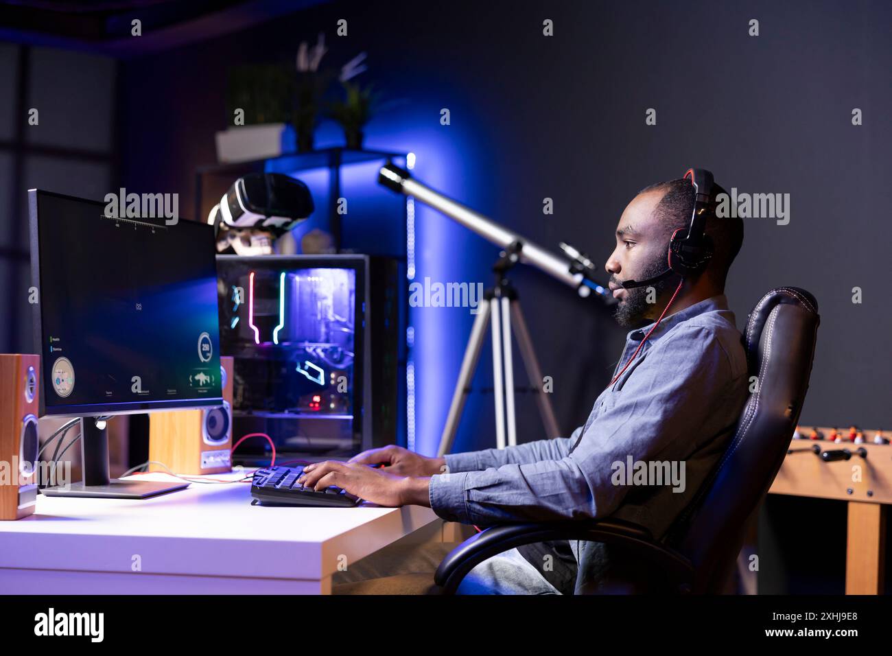Man in RGB lit apartment playing immersive video games on desktop PC at ...