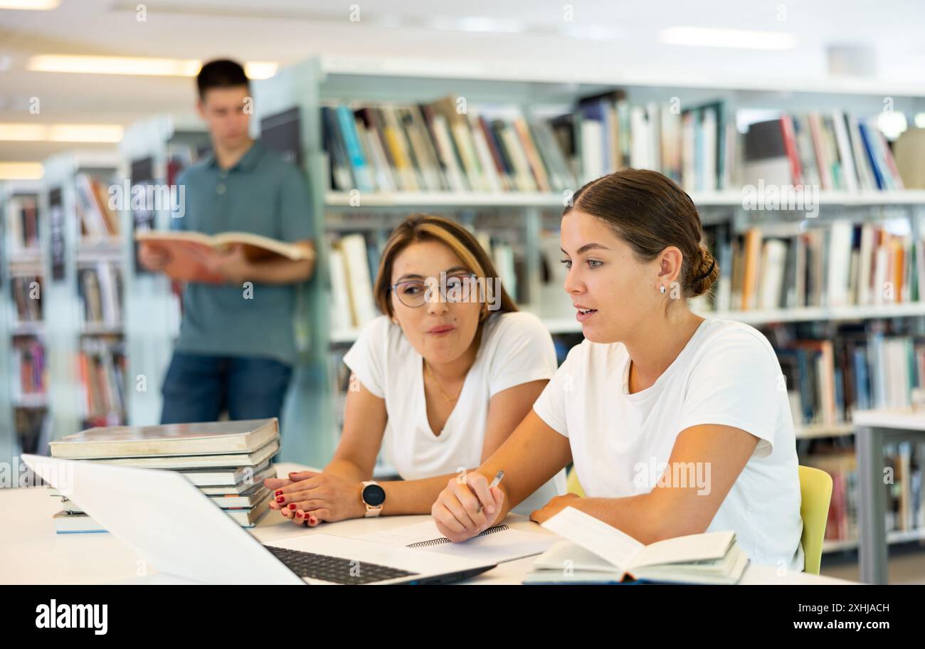 Skilled female students research together in library Stock Photo - Alamy
