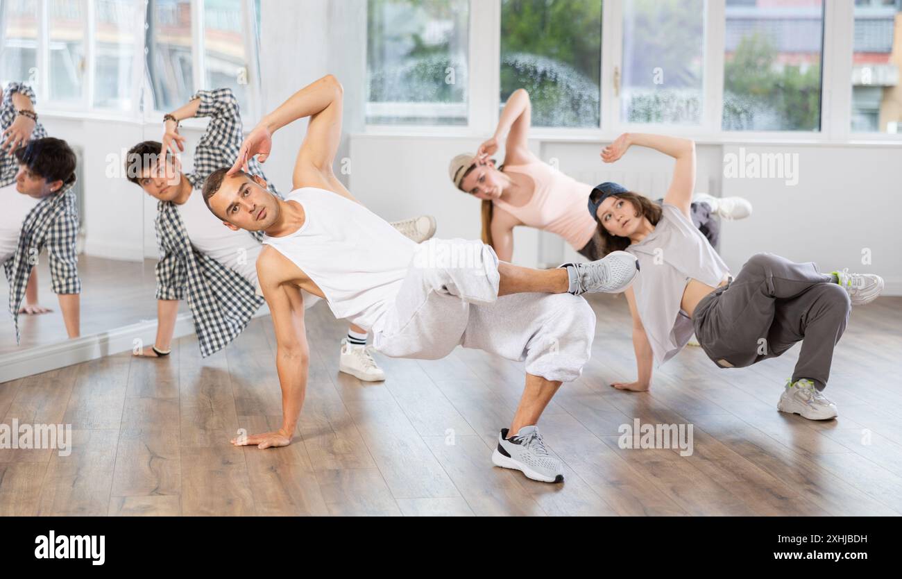 Man and his students perform hip hop dance on one bent leg, movement in ...