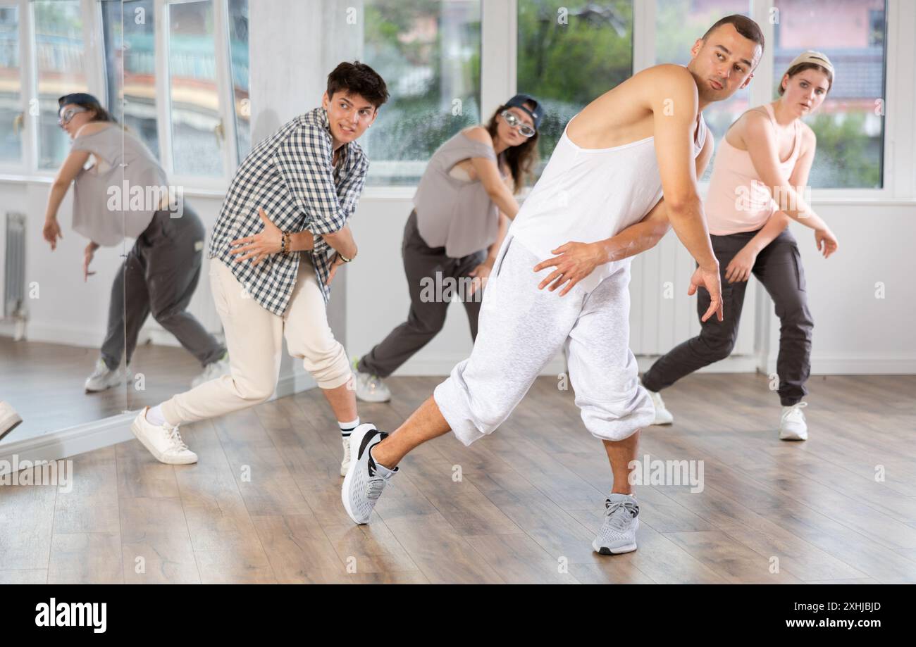 Young man standing performs basic hip hop movements in front of group ...