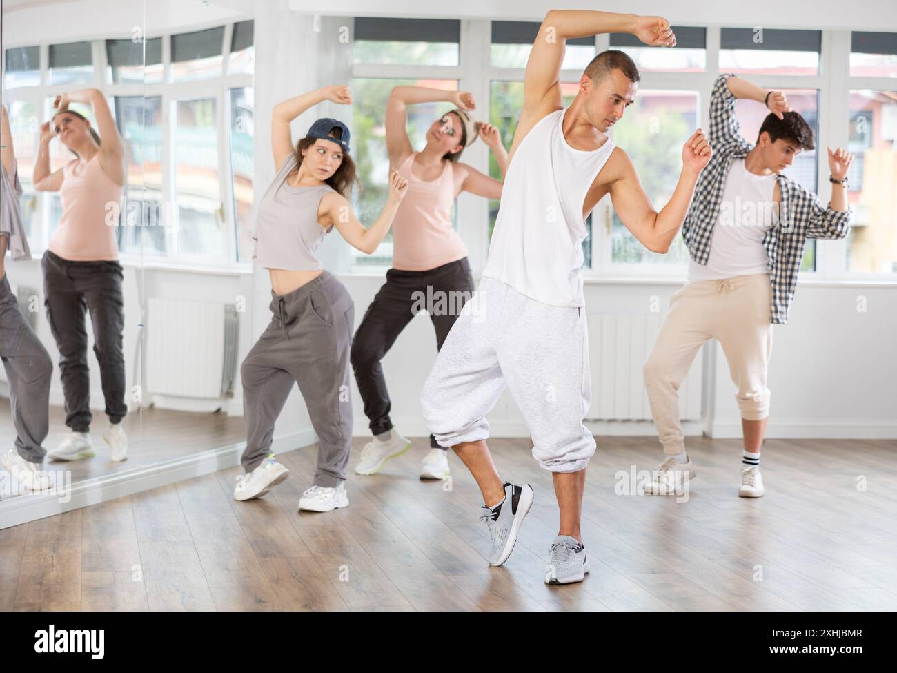 Young man standing performs basic hip hop movements in front of group ...