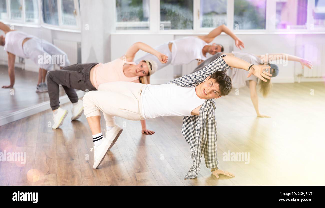 Man and his students perform hip hop dance on one bent leg, movement in ...