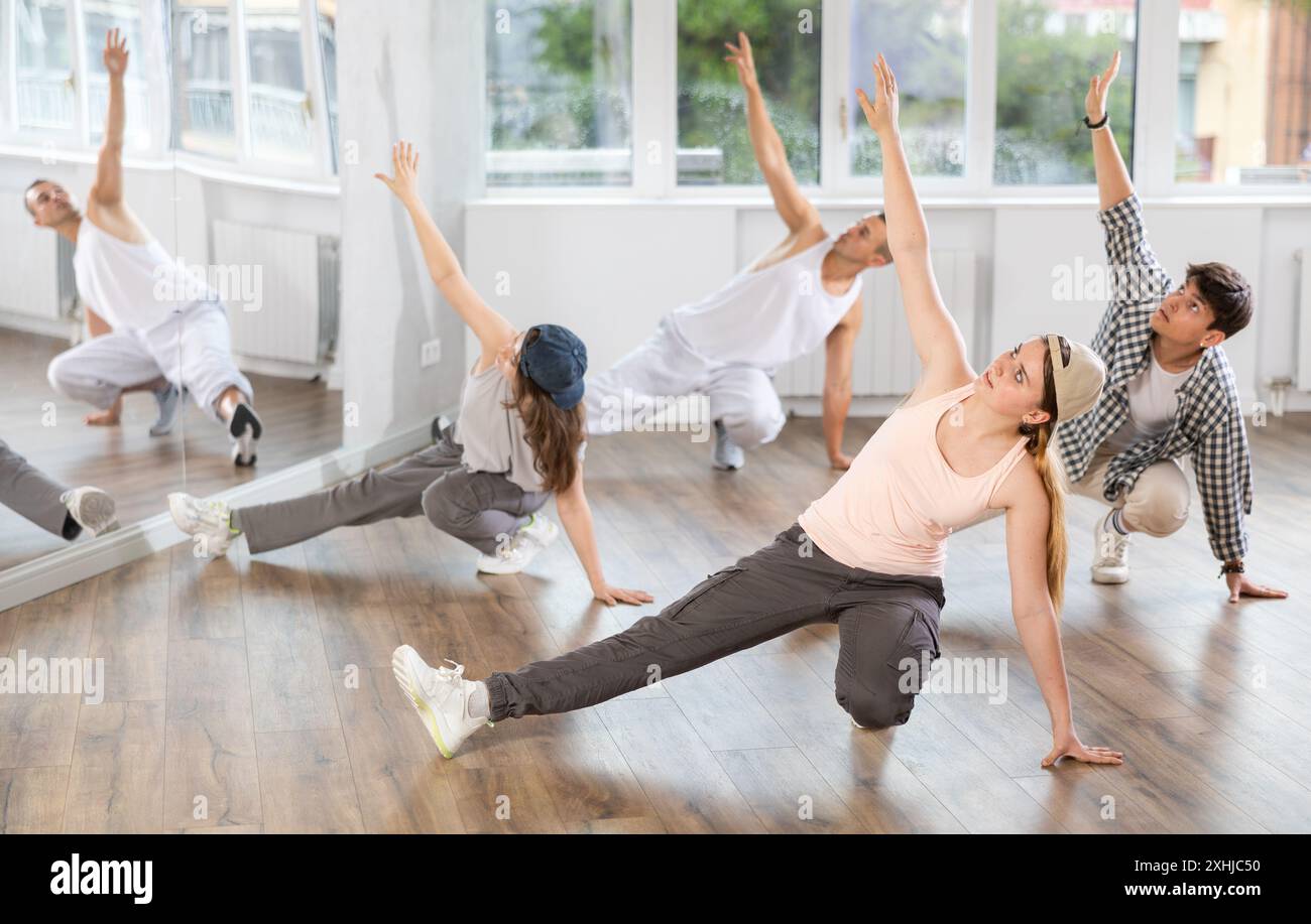 Girl and her students perform hip hop dance on one bent leg, movement ...