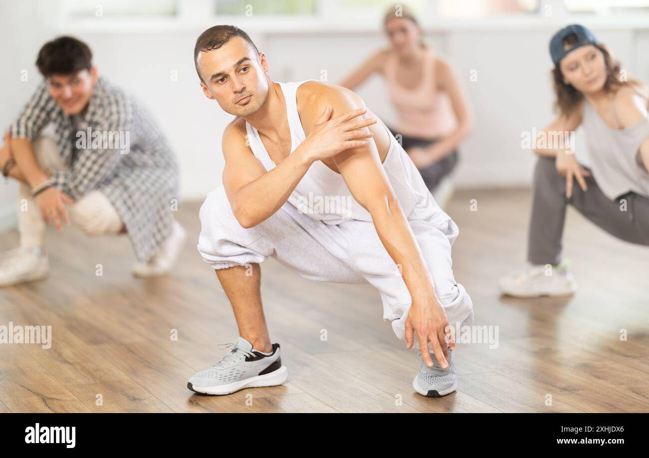 Young guy performing sitting pose of breakdance in training hall Stock ...