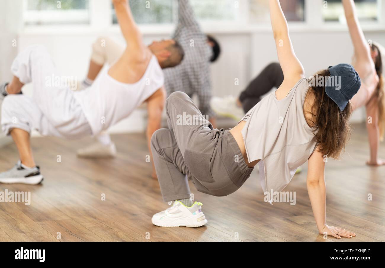 Girl and her students perform hip hop dance on one bent leg, movement ...
