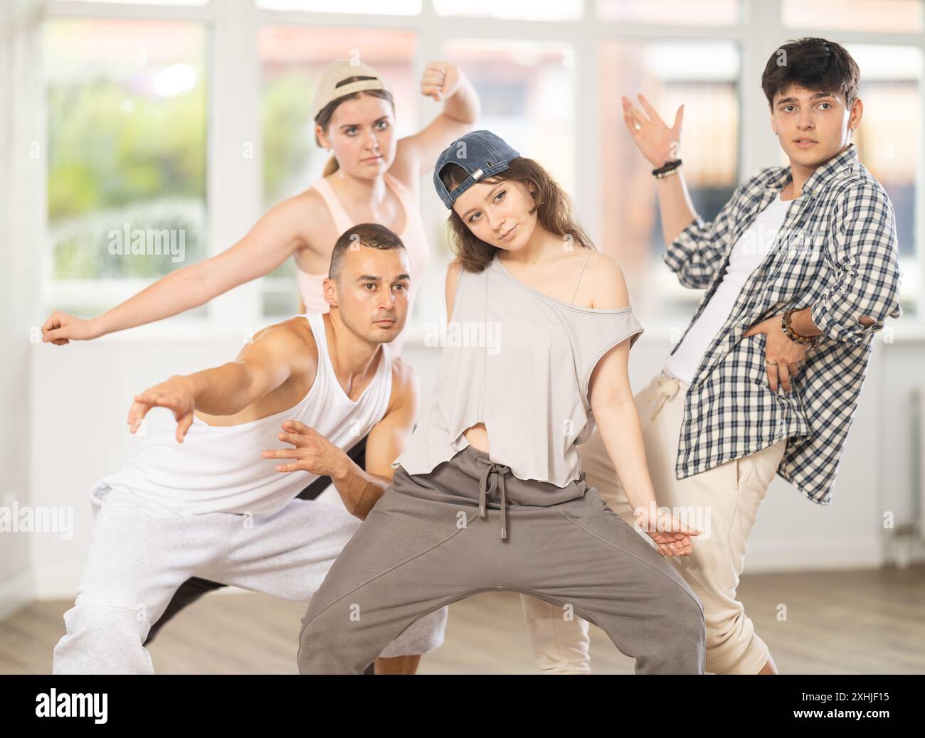 Active girls and guys demonstrating breakdance poses in training hall ...