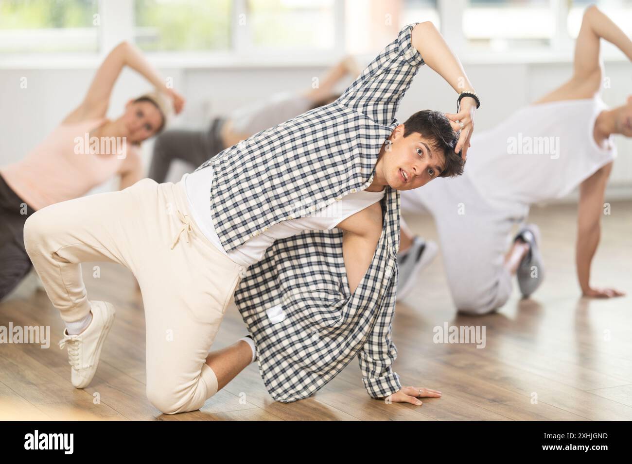 Man and his students perform hip hop dance on one bent leg, movement in ...