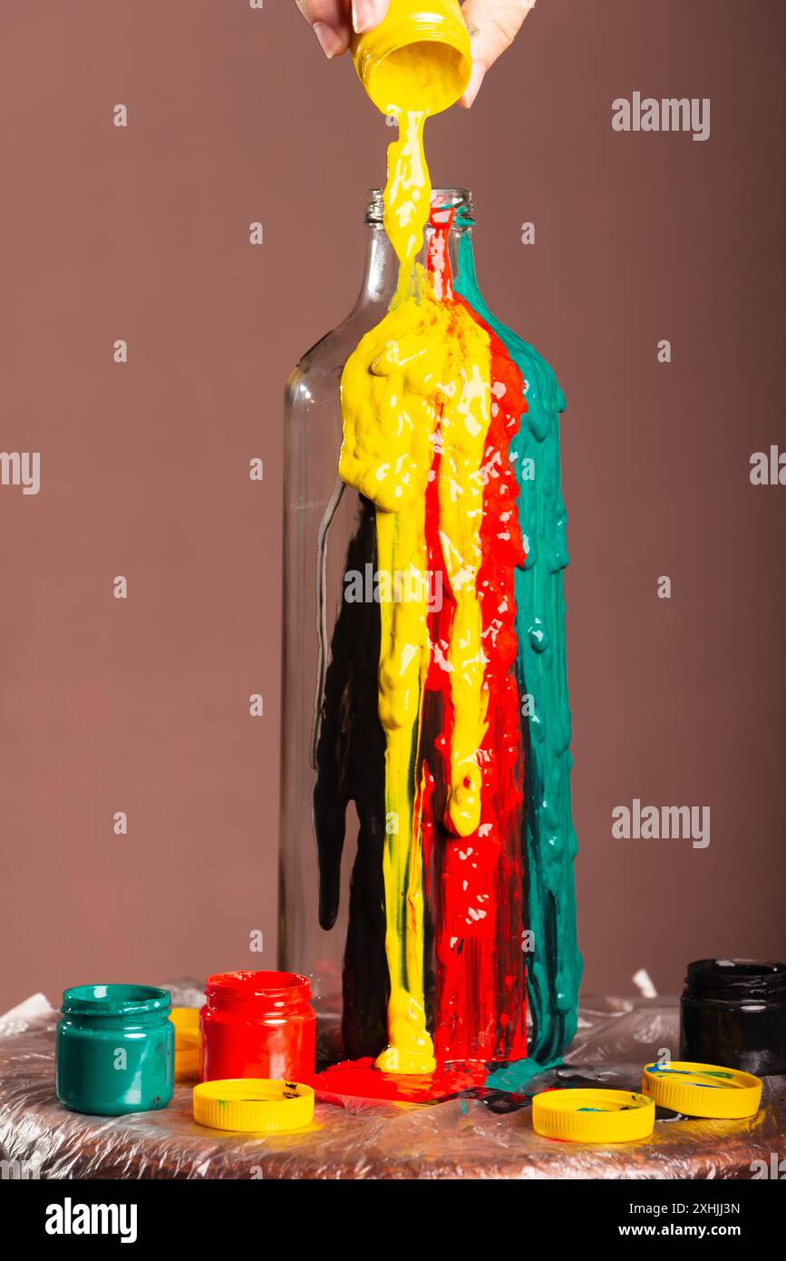 Painter pouring yellow paint into a glass bottle. abstract art ...