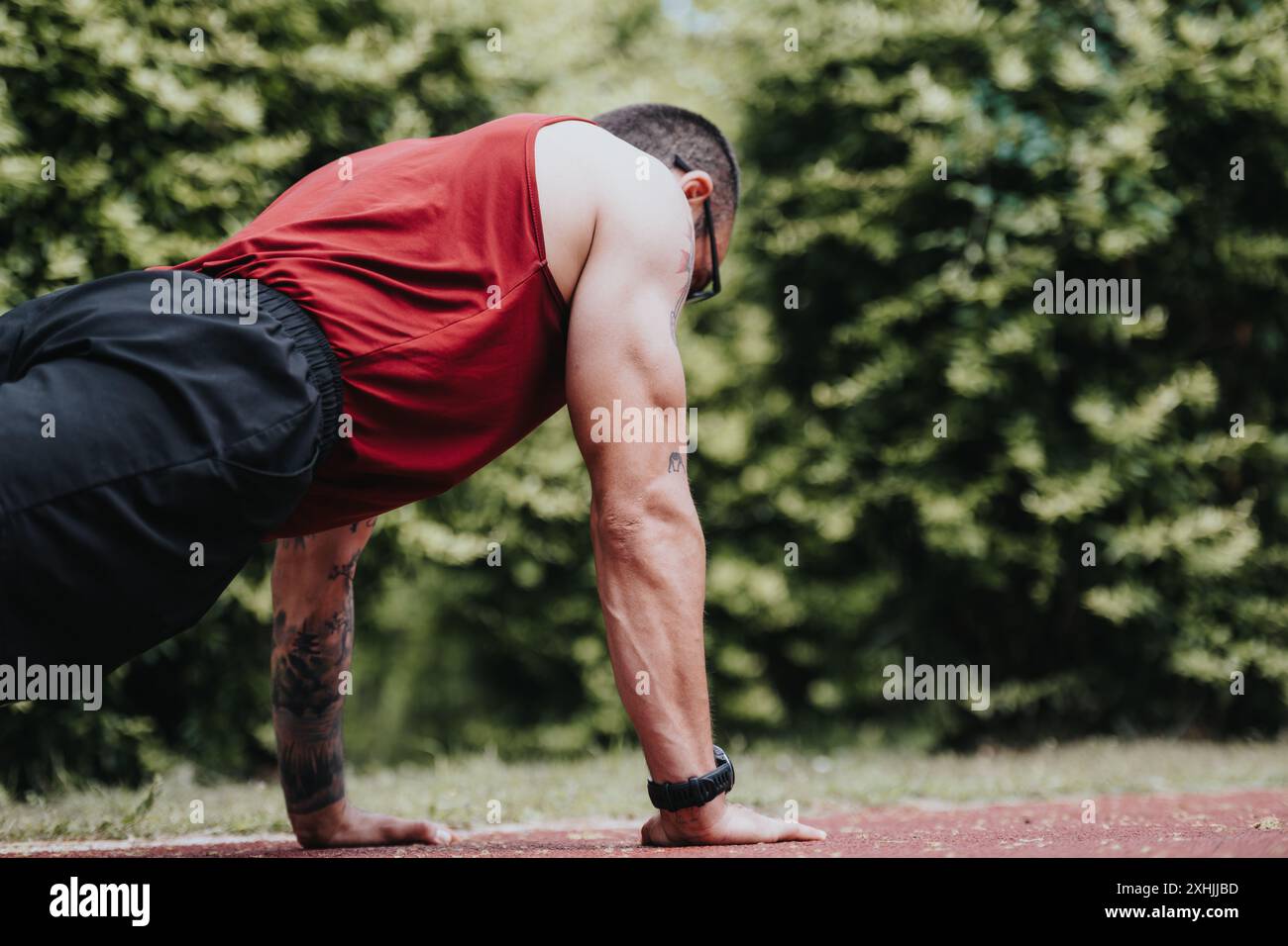 Fit young man performs push-ups in a park, showcasing dedication and ...