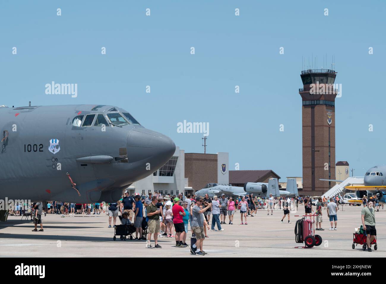 A crowd walks around the flightline looking at a B-52 Stratofortress ...