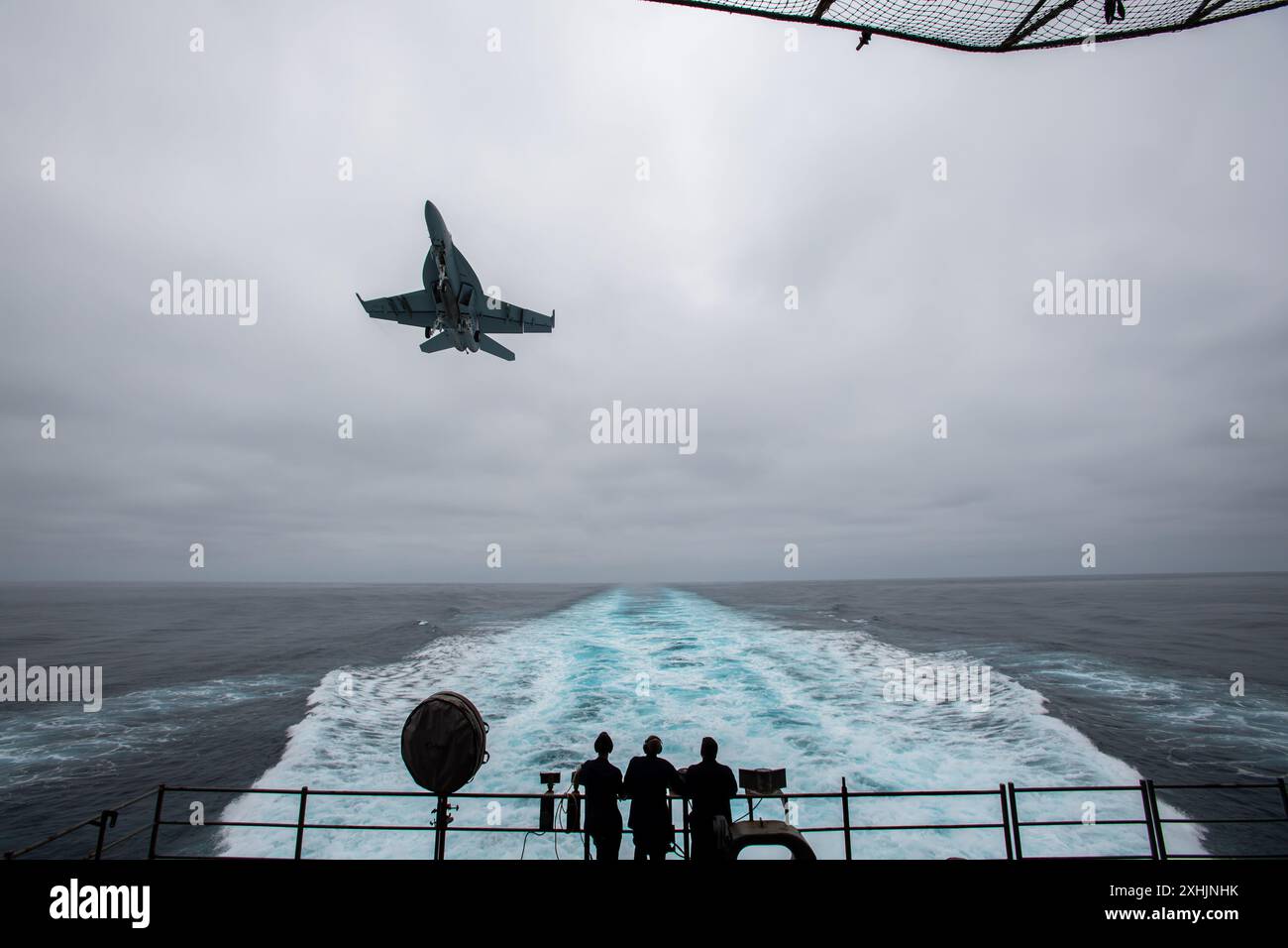 Sailors observe an F/A-18F Super Hornet approach the aircraft carrier ...
