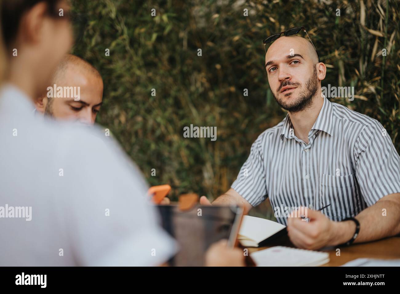 Young men engaging in business meeting discussion at outdoor cafe with ...