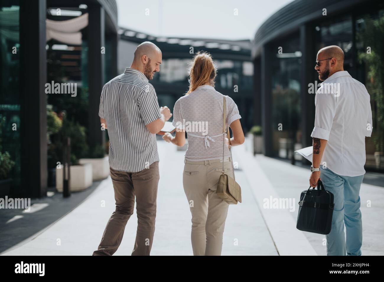 Group of colleagues walking together outdoors in a modern urban setting ...