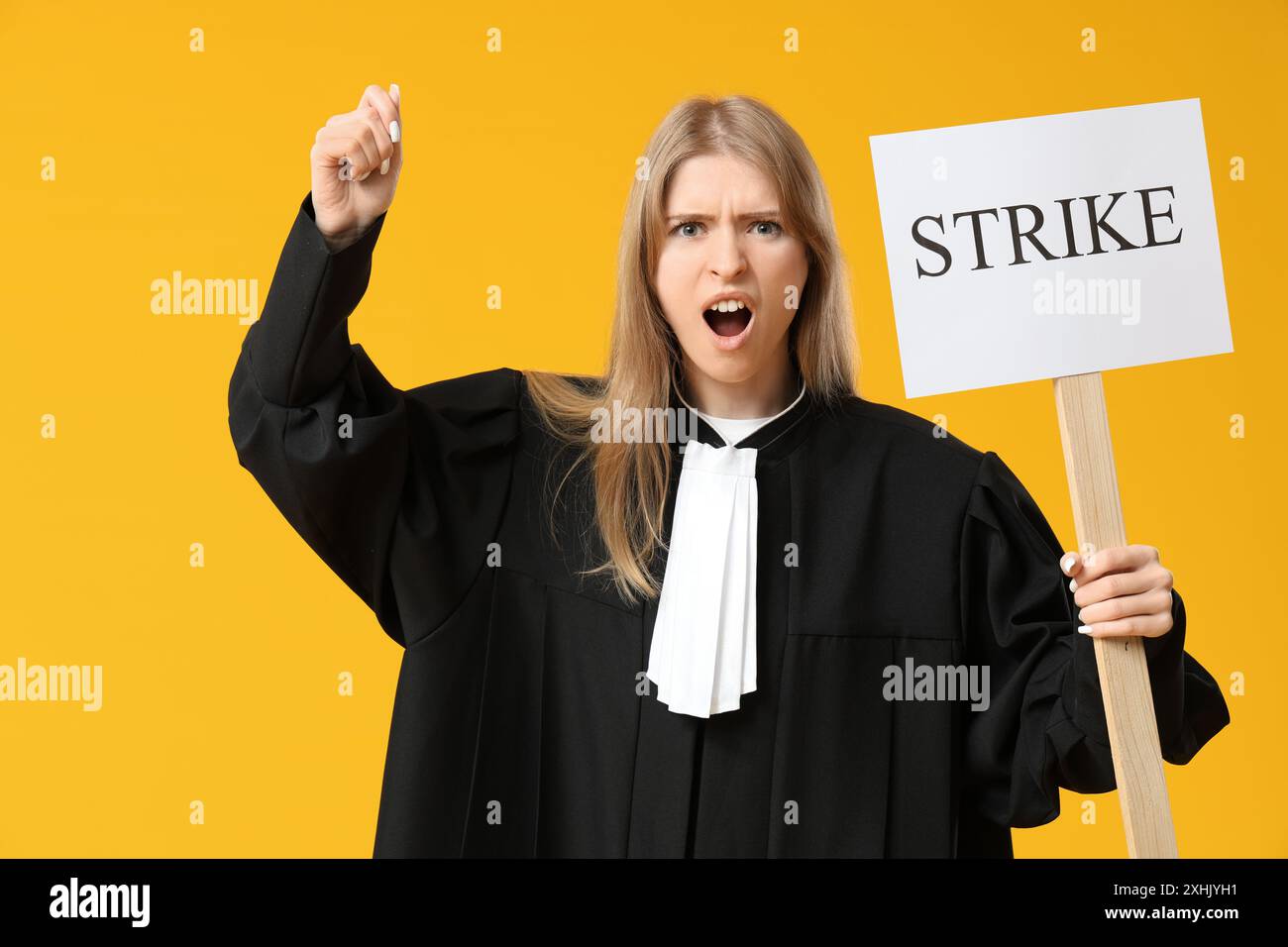 Protesting female judge holding placard with text STRIKE on yellow ...
