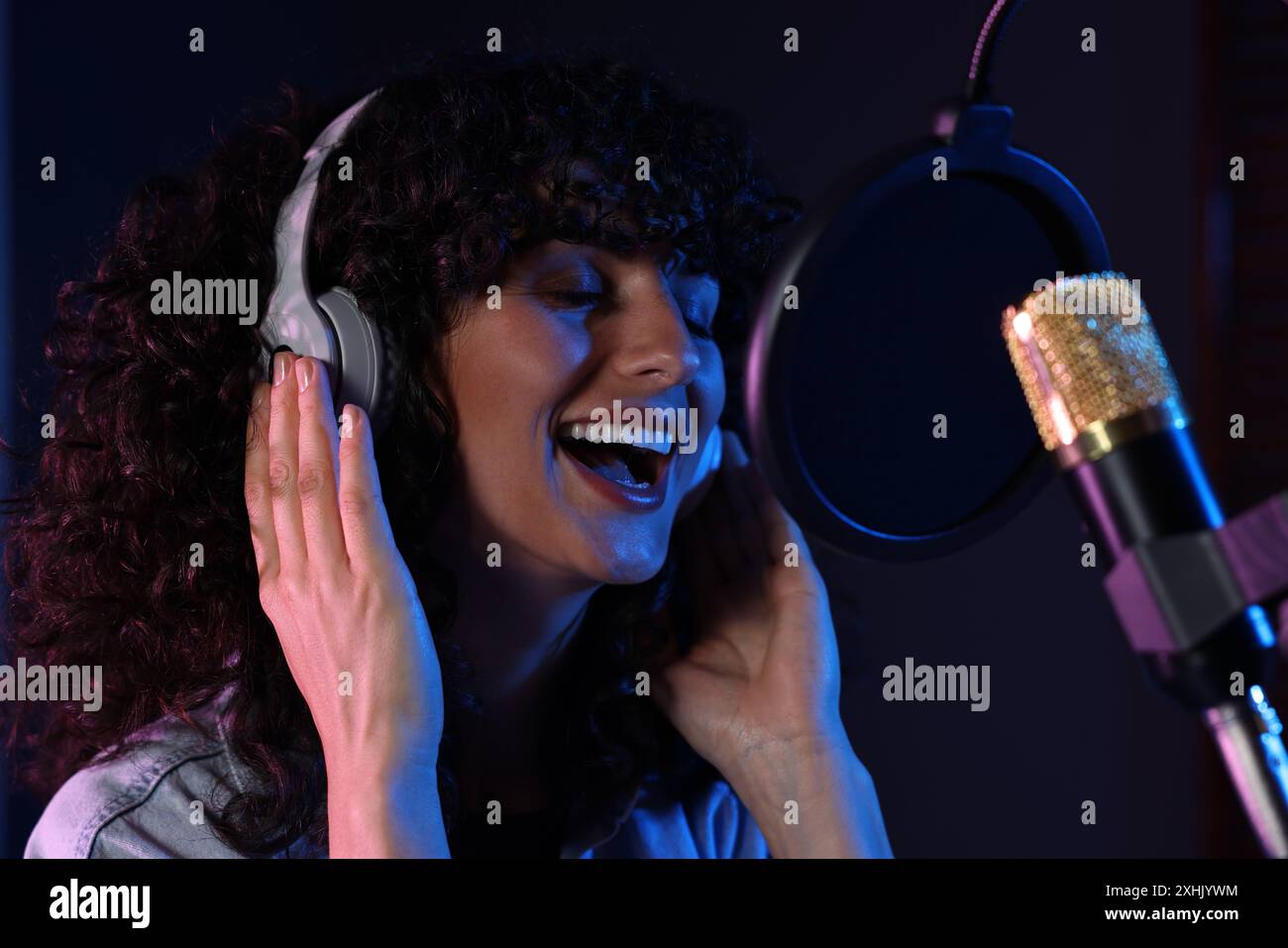 Vocalist with headphones singing into microphone in professional record ...