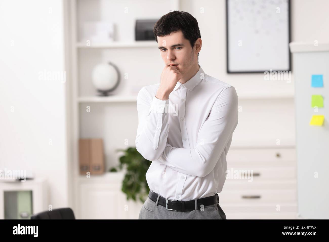 Portrait of embarrassed young man in office Stock Photo - Alamy