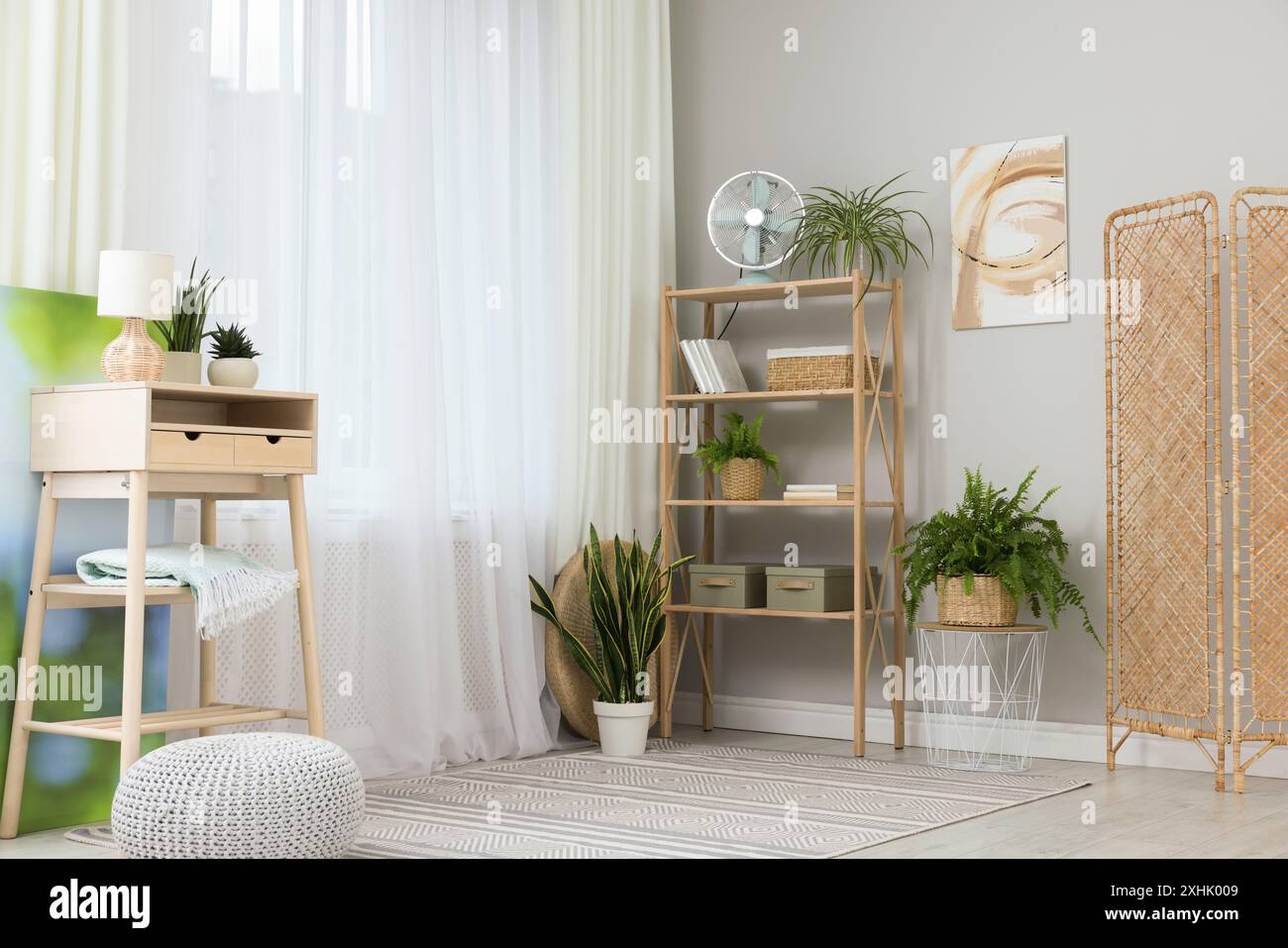 Window with beautiful curtains, pouf, houseplants and furniture in room ...