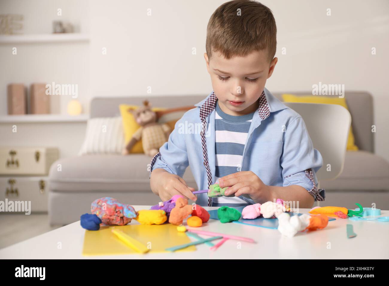 Little boy sculpting with play dough at table in kindergarten Stock ...