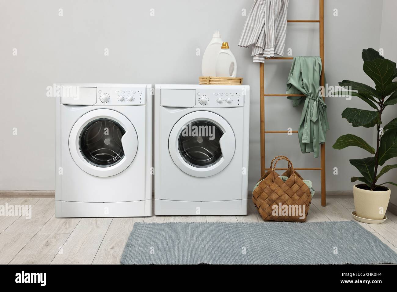 Two washing machines near light grey wall in laundry room Stock Photo ...
