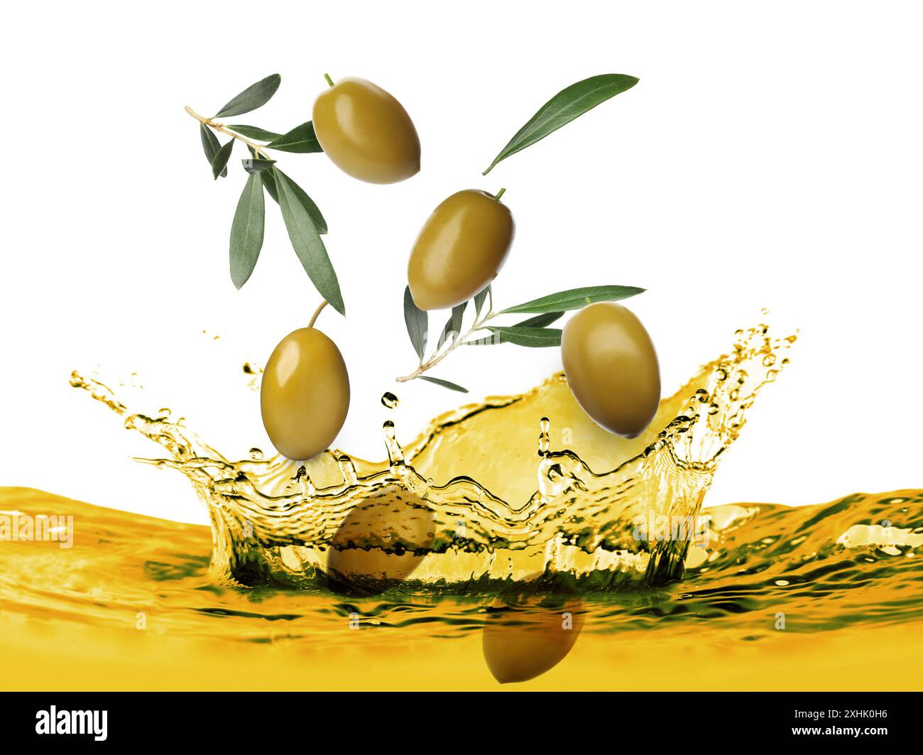 Green olives and leaves falling into cooking oil on white background ...