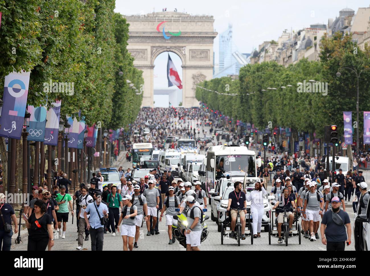 A torchrunner waves a hand on Avenue des Champs-Élysées ahead of the ...
