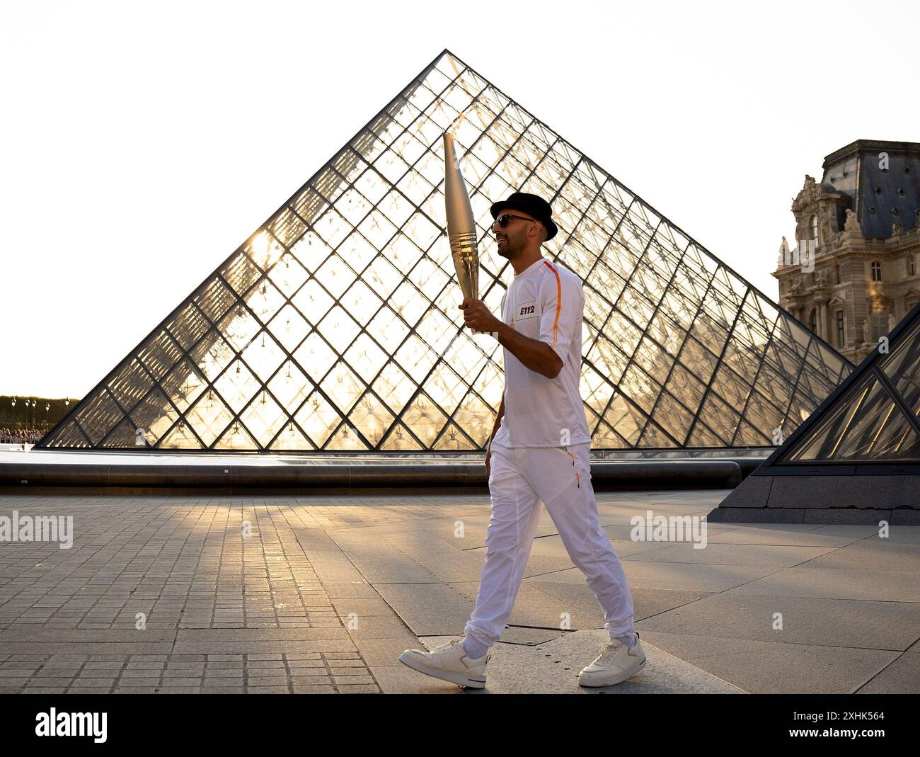Paris, France. 14th July, 2024. Torch bearer Jean Rene holds the ...