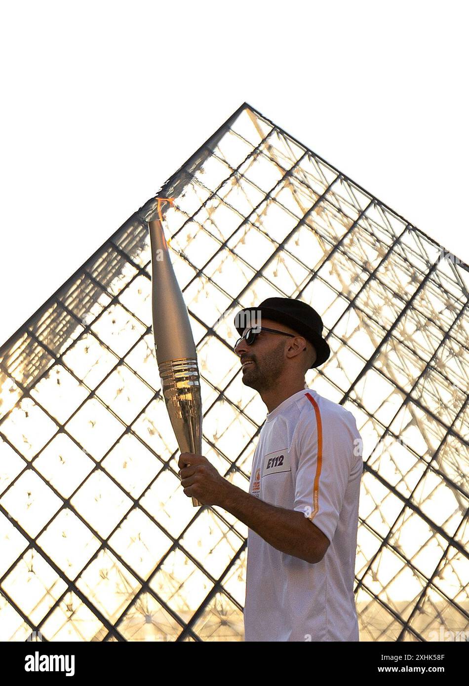 Paris, France. 14th July, 2024. Torch bearer Jean Rene holds the ...