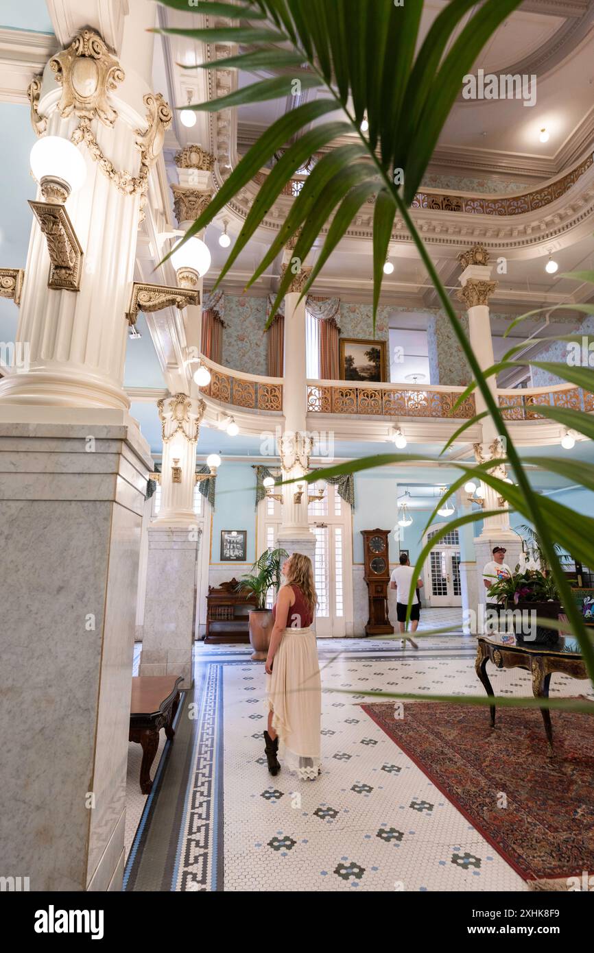 Female guest walks around the gilded lobby atrium where famous people socialized in the past ...