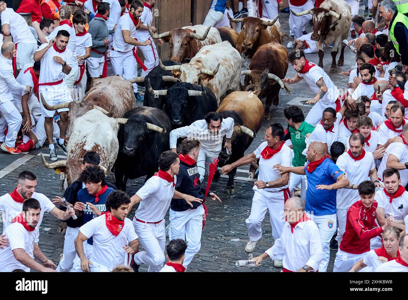 Several runners run in front of the bulls through the streets of ...