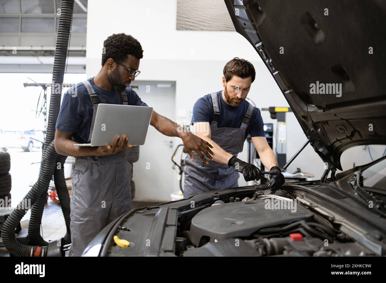 Two mechanics working on car engine in garage Stock Photo - Alamy