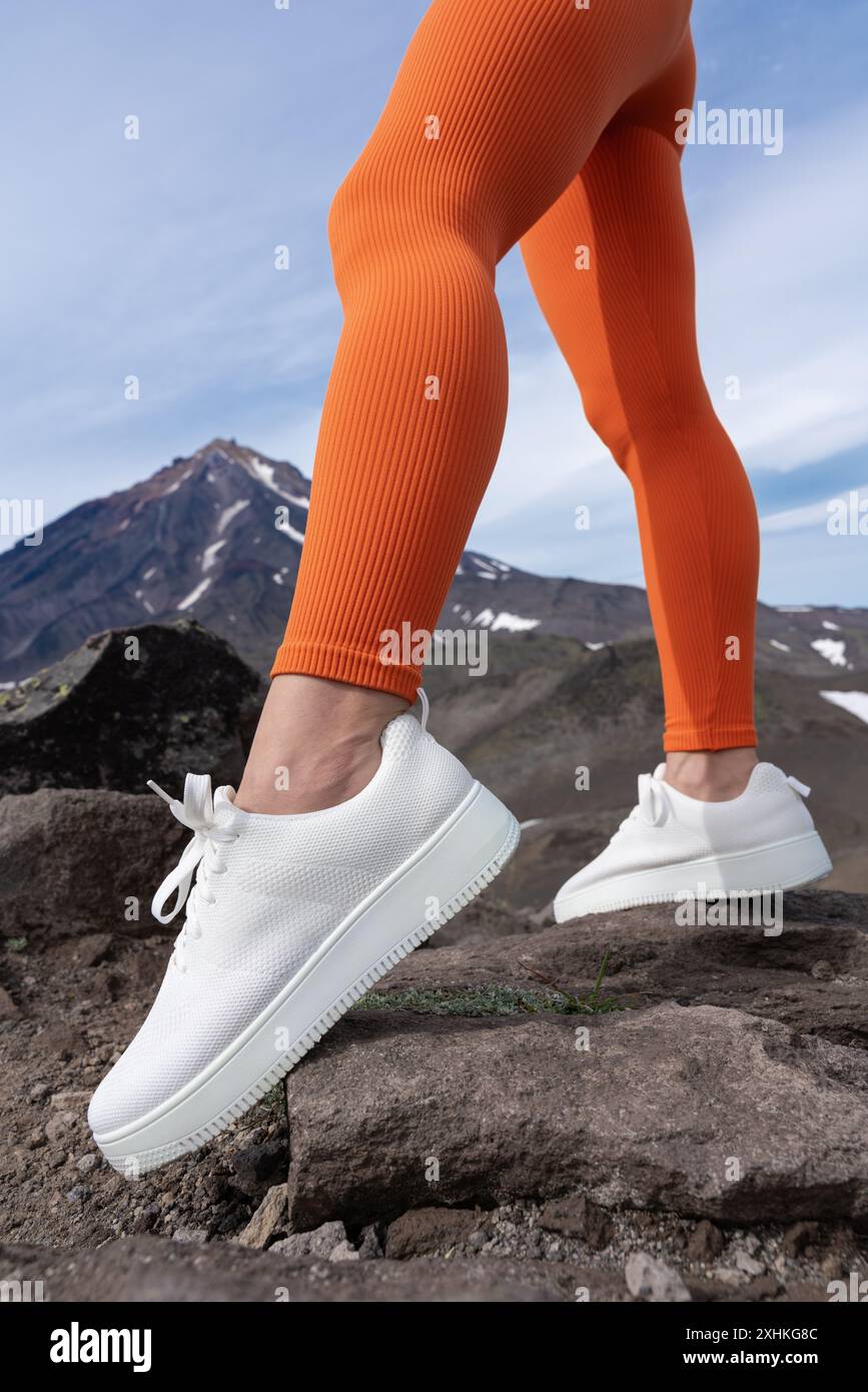 Athletic female legs wearing orange fit leggings and white sneakers ...
