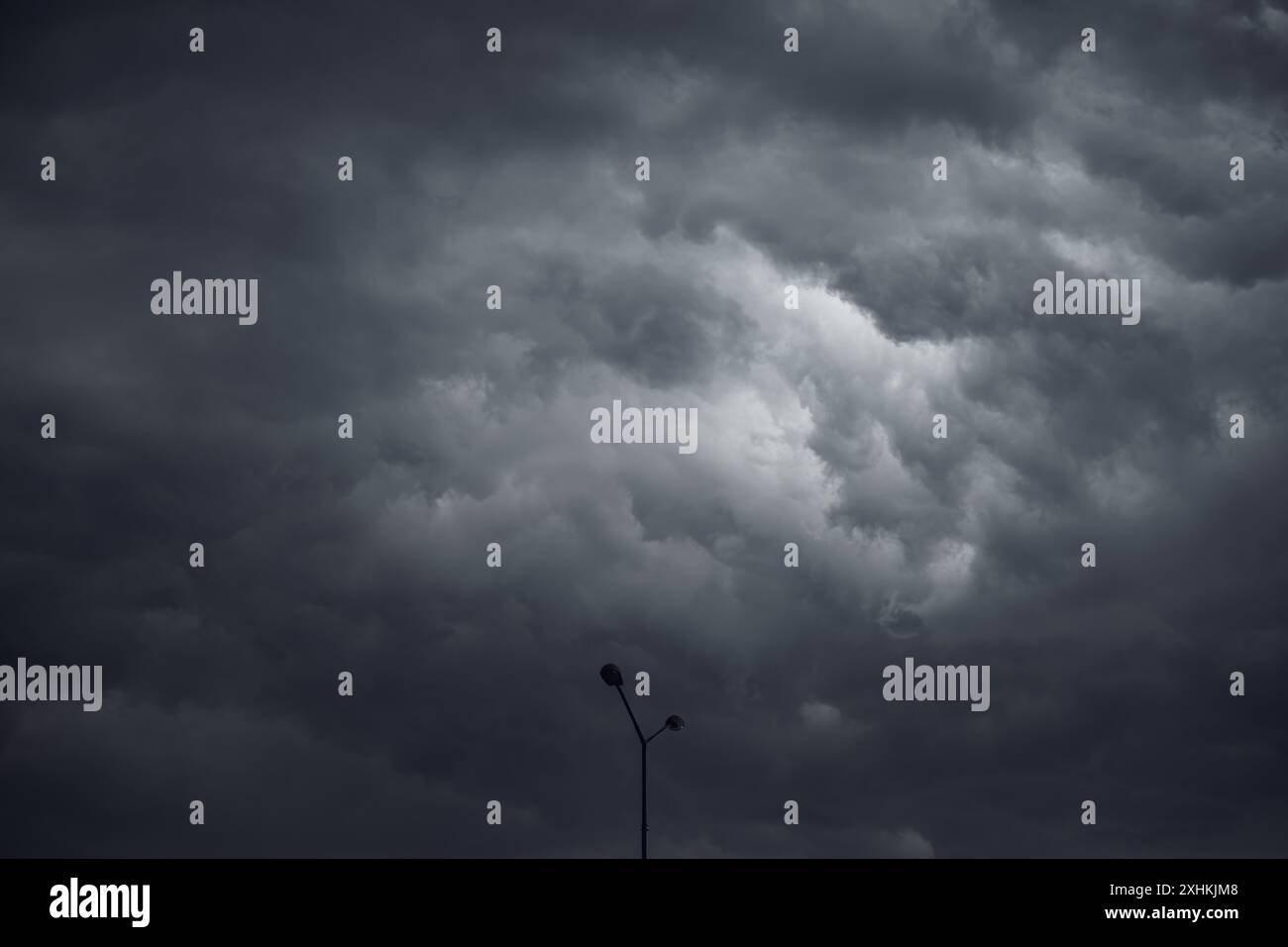 Silhouette of street lamp post against dark stormy clouds in summer ...