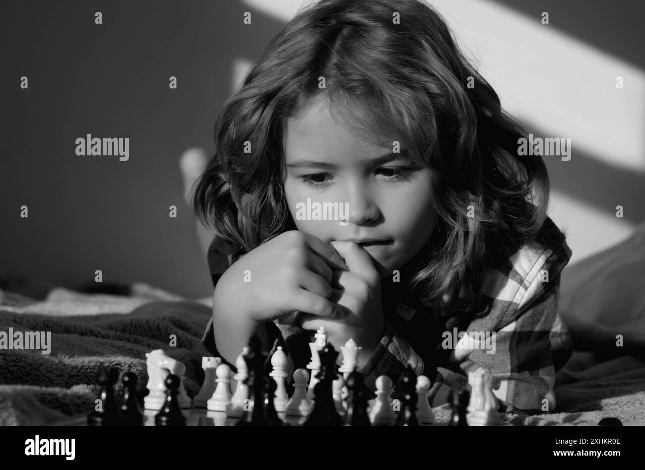 Little boy are playing chess at home. Clever concentrated and thinking ...