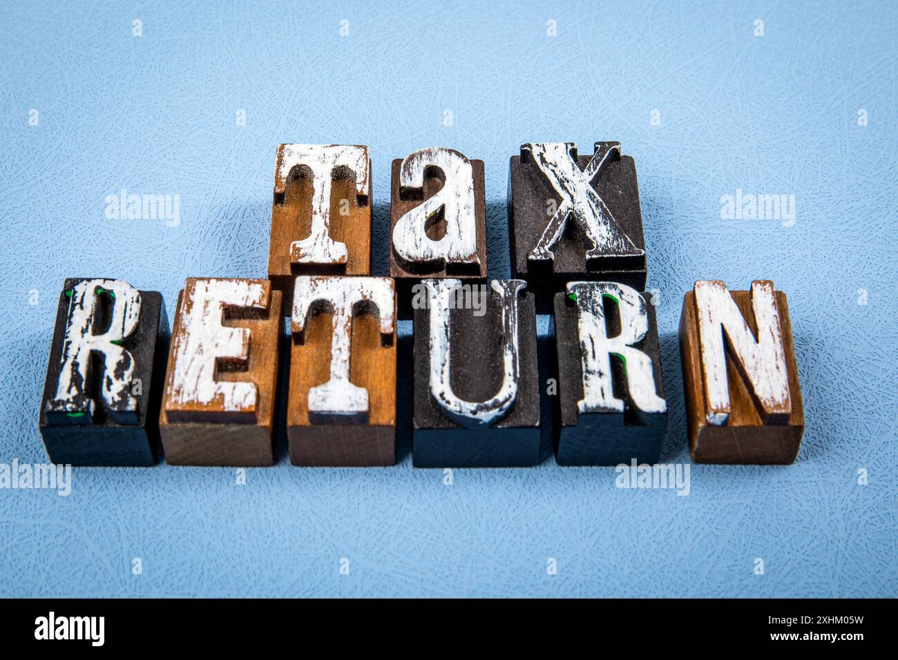 TAX RETURN. Wooden alphabet letter blocks on blue textured background ...