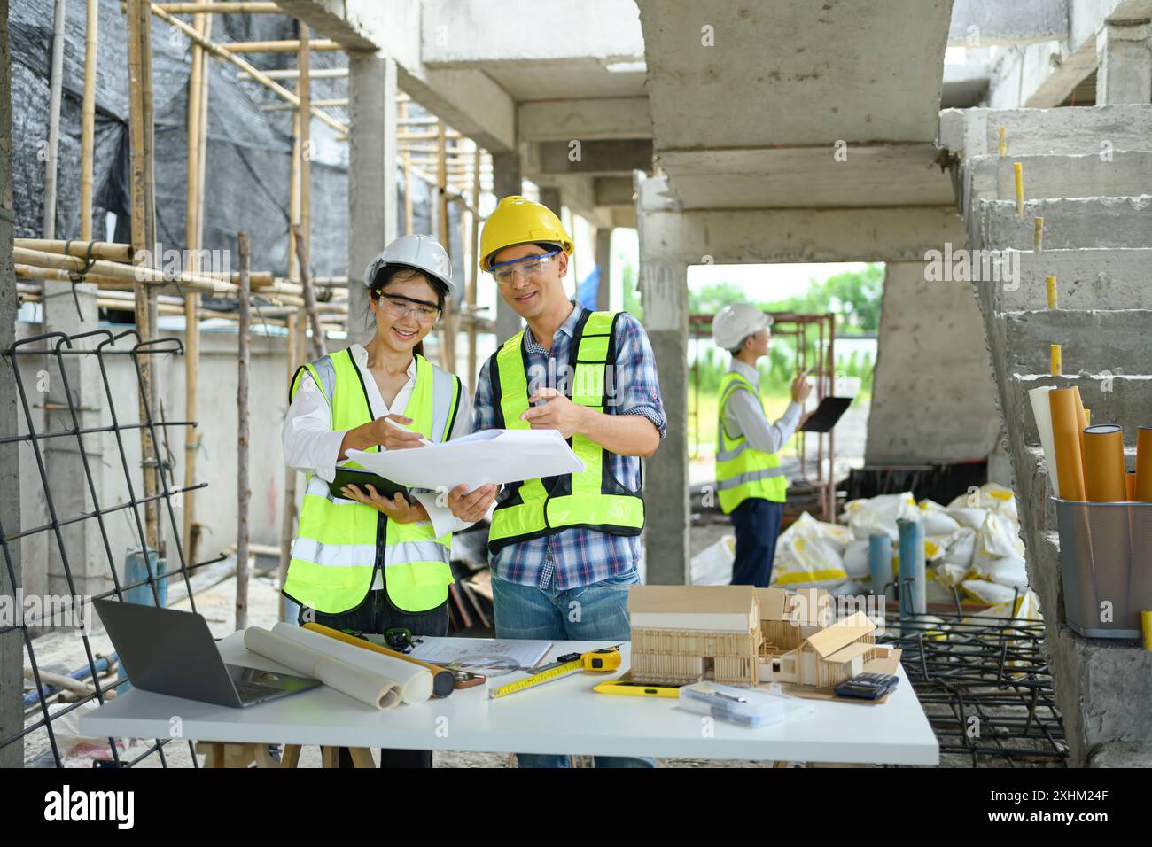 Specialists team in safety vest and helmet discussing structure of the building at construction ...