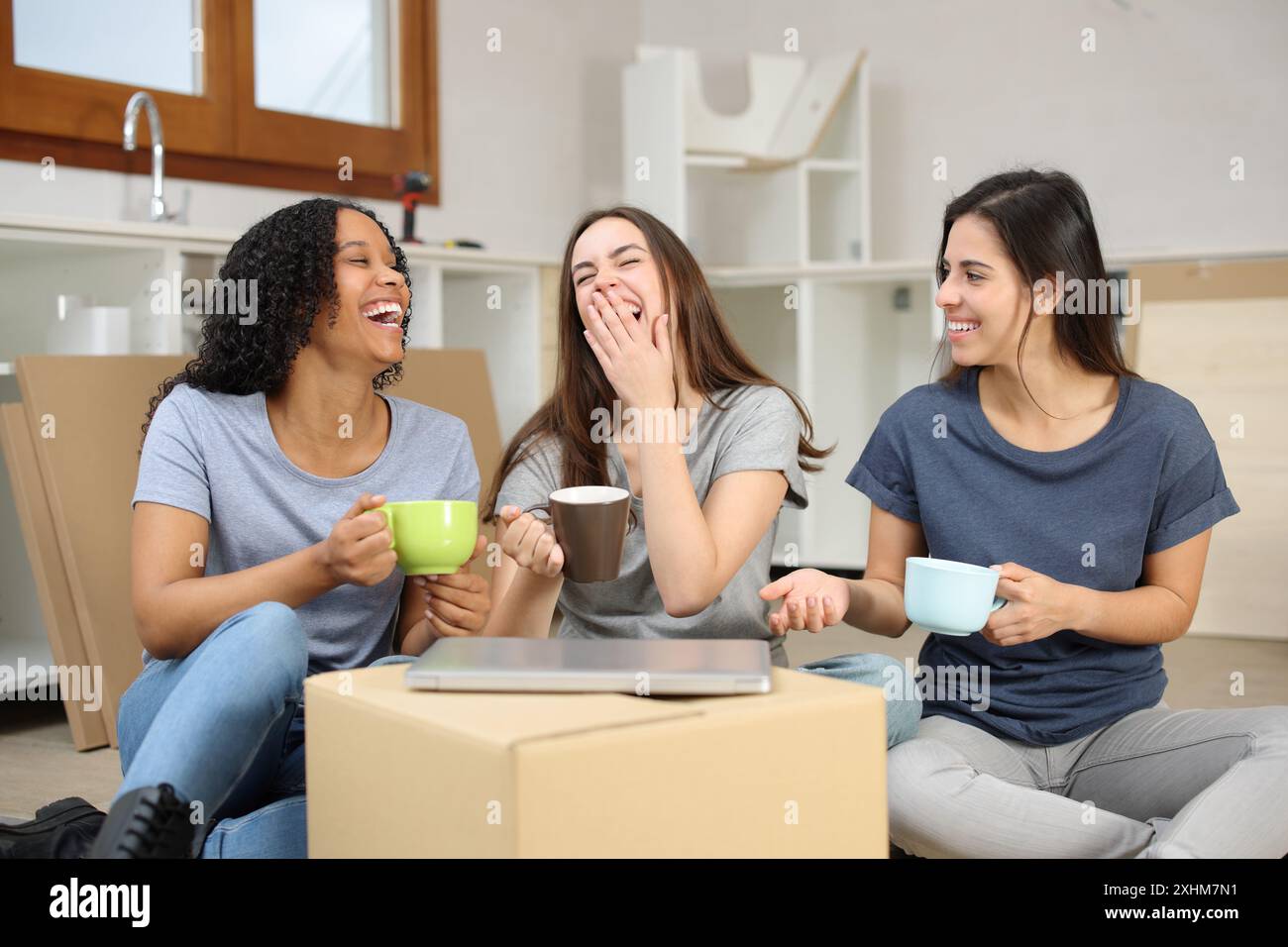 Funny roommates laughing resting and drinking while moving house Stock ...