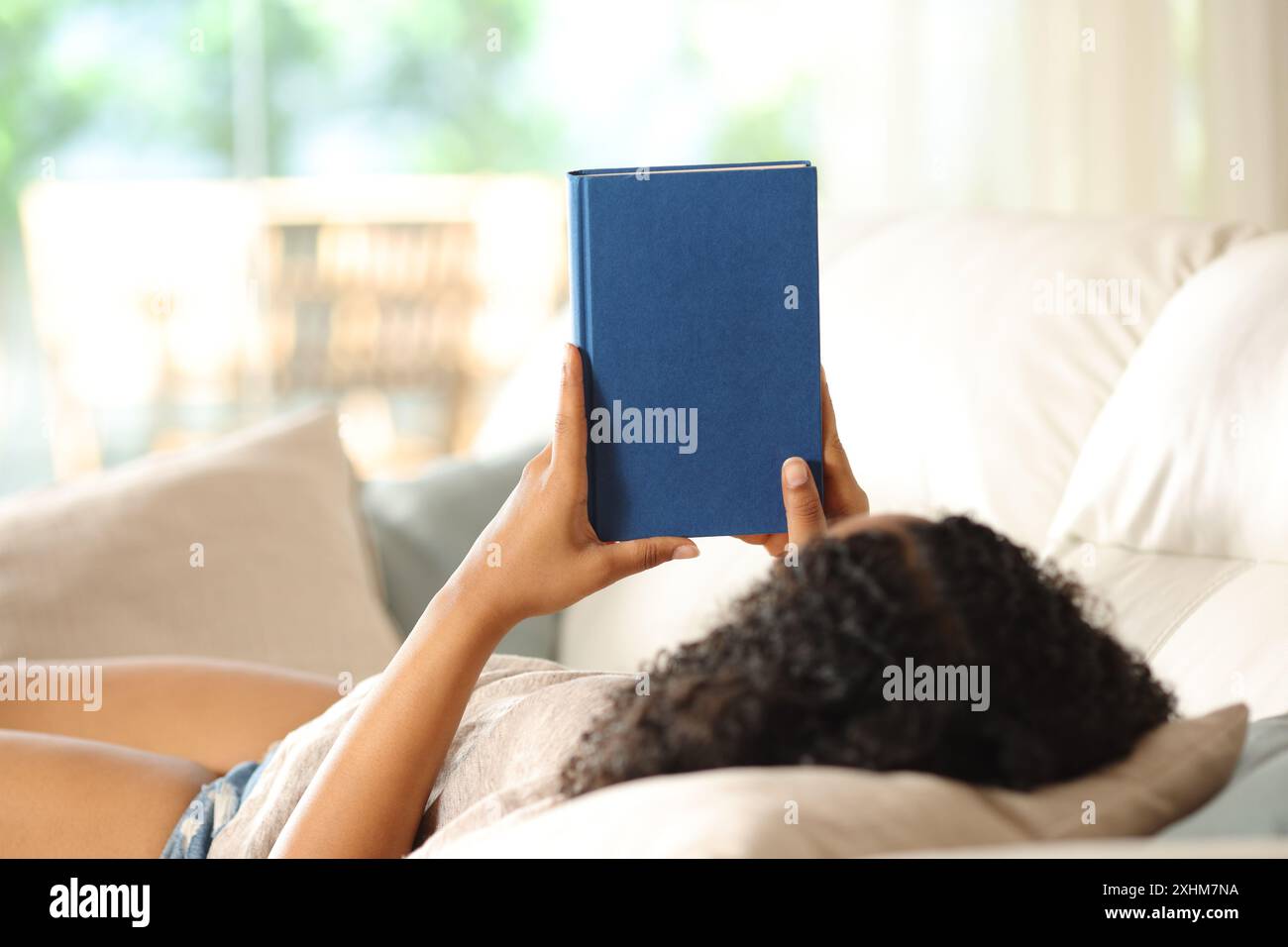 Black woman watching blank book cover lying on a couch at home Stock ...