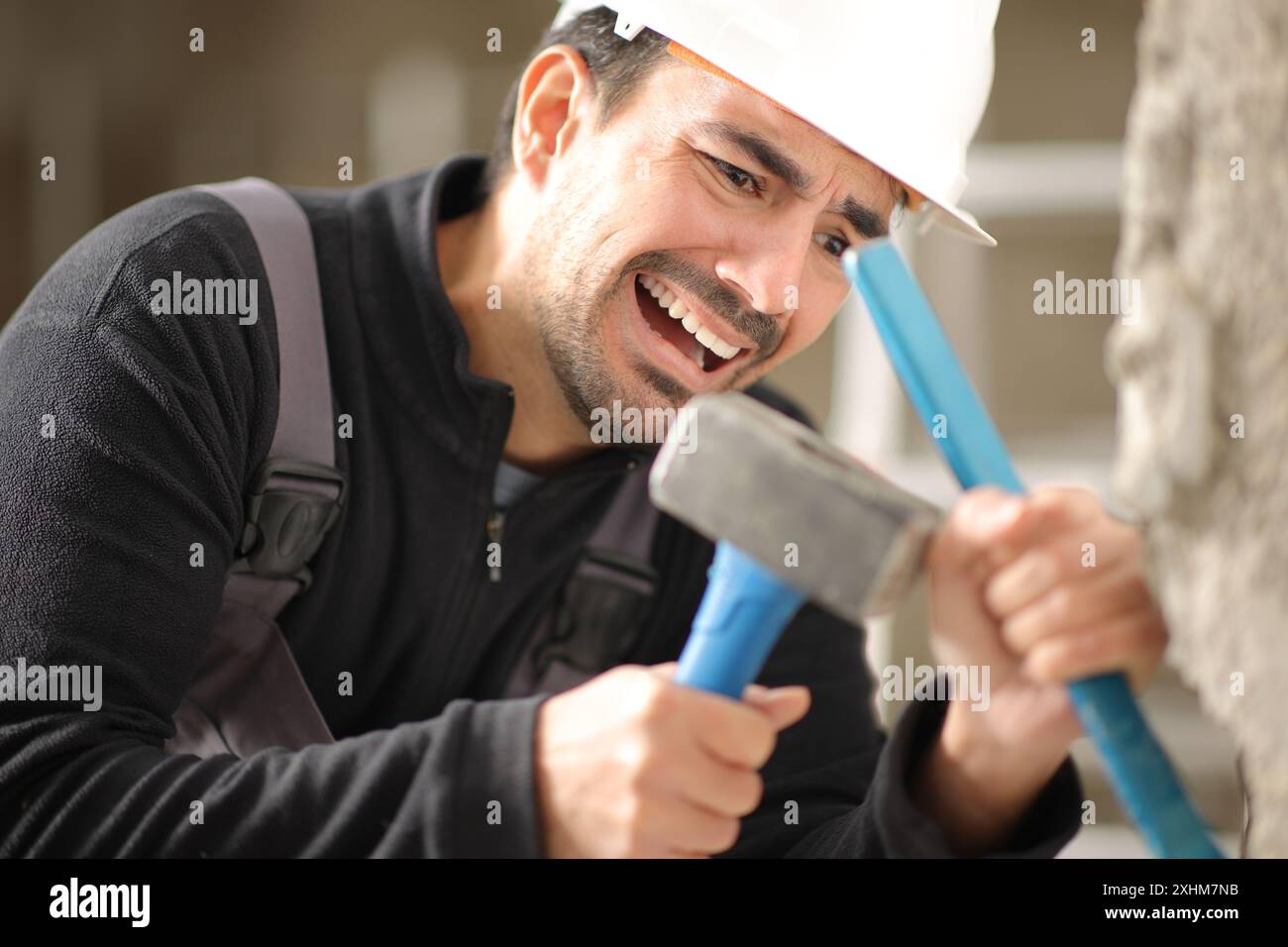 Construction worker suffering accident hiting hand with hammer working ...