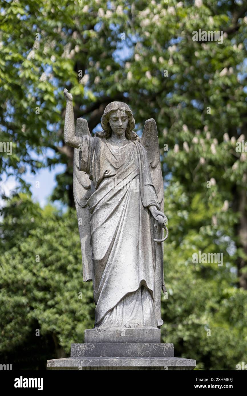 A winged angel statue on a grave, with raised hand as though blessing ...