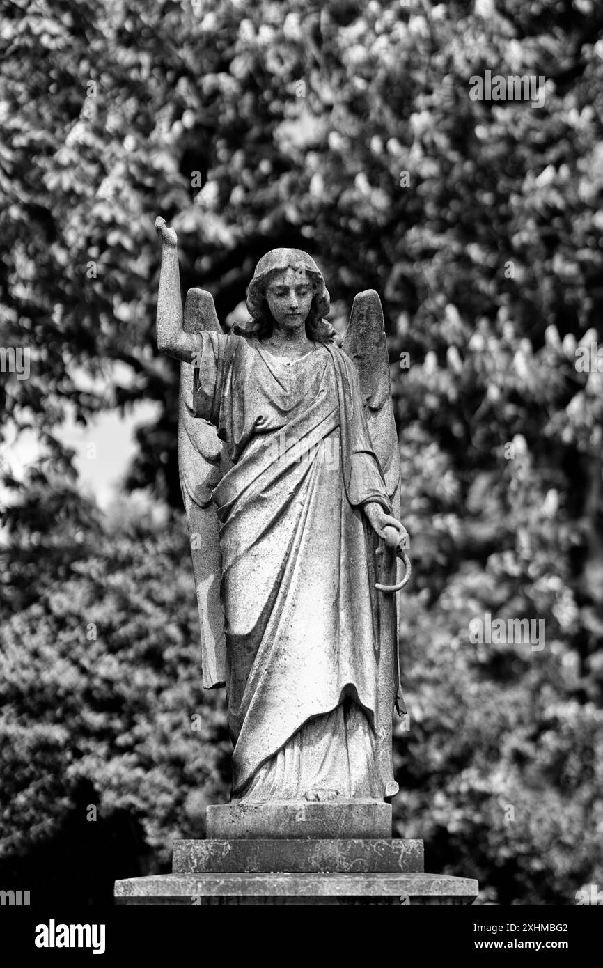 A winged angel statue on a grave, with raised hand as though blessing ...