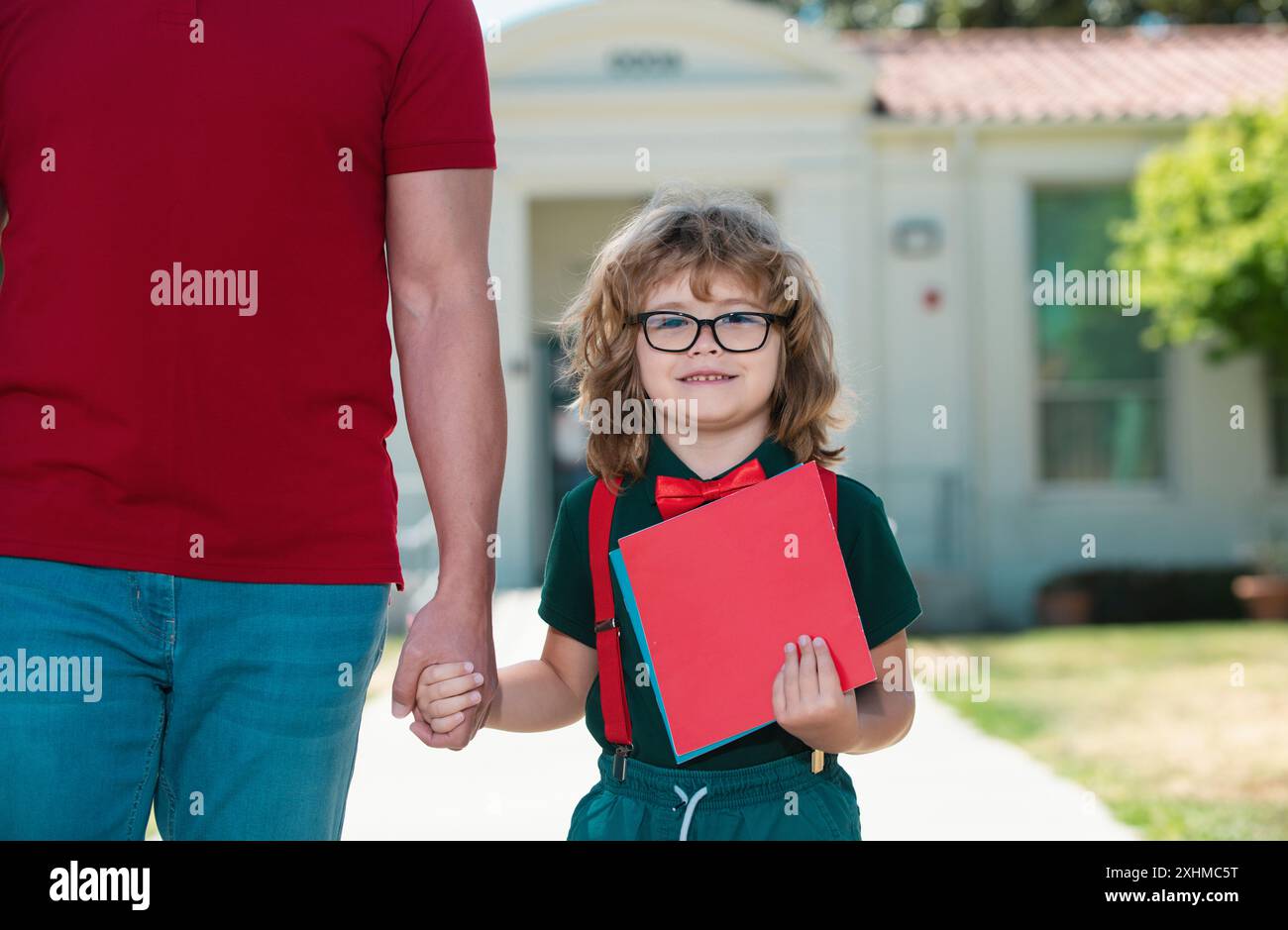 Portrait of happy nerd pupil holding teachers hand. Father and son ...