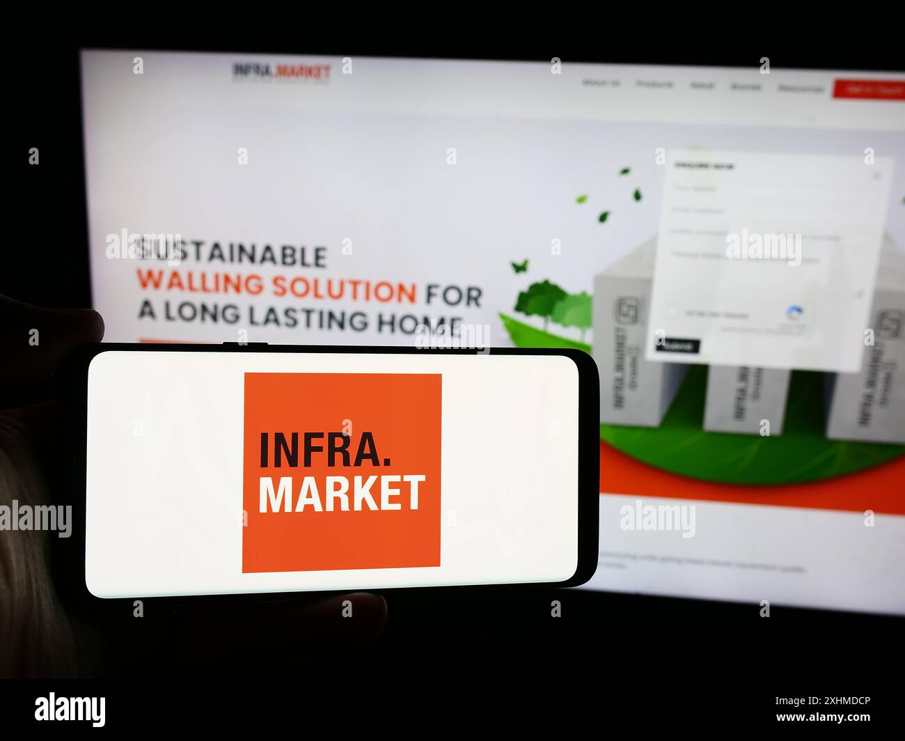 Person holding smartphone with logo of Indian company Hella Infra ...