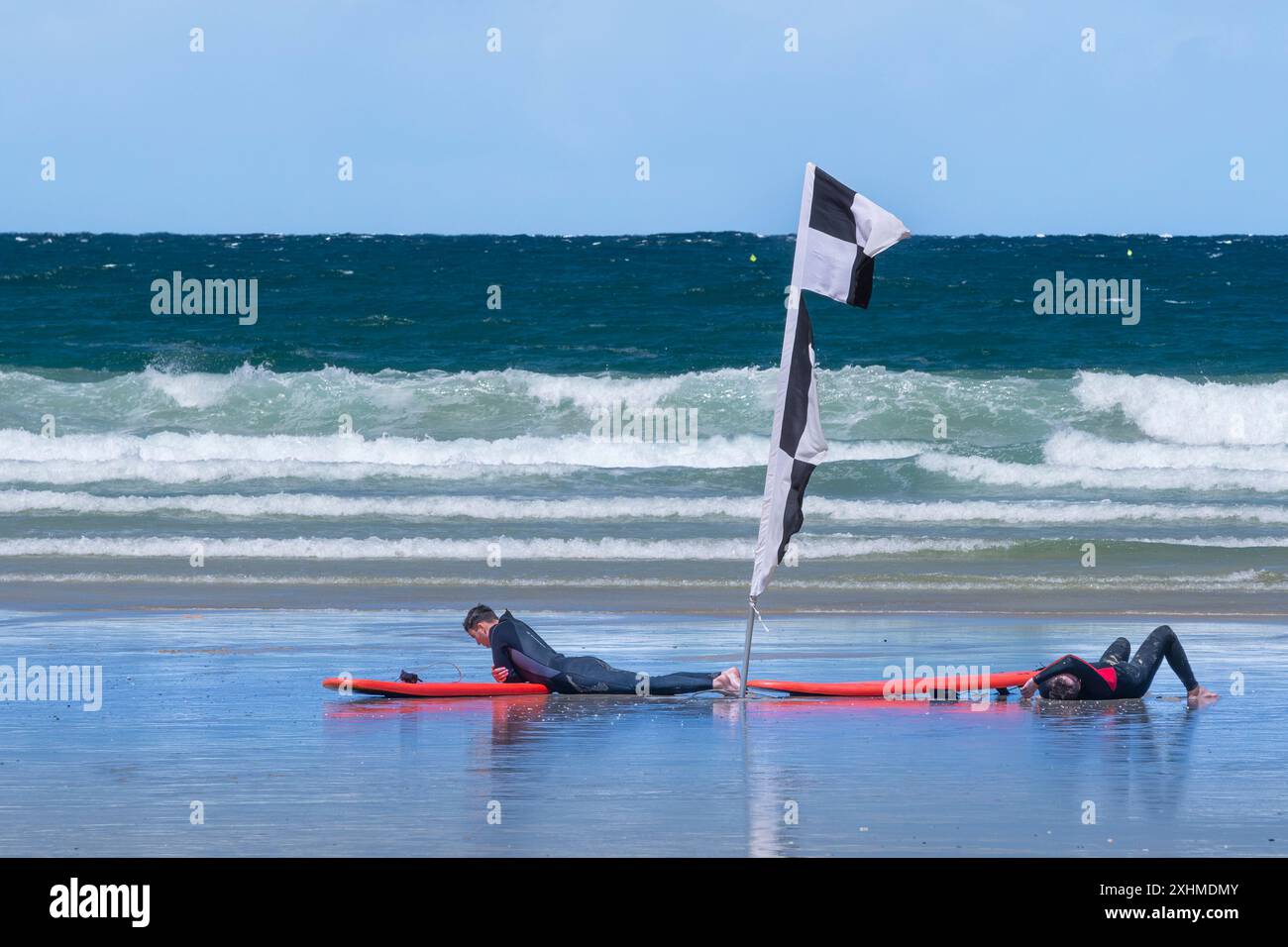 Two tired surfers taking a break and resting on their surfboards on Gt ...