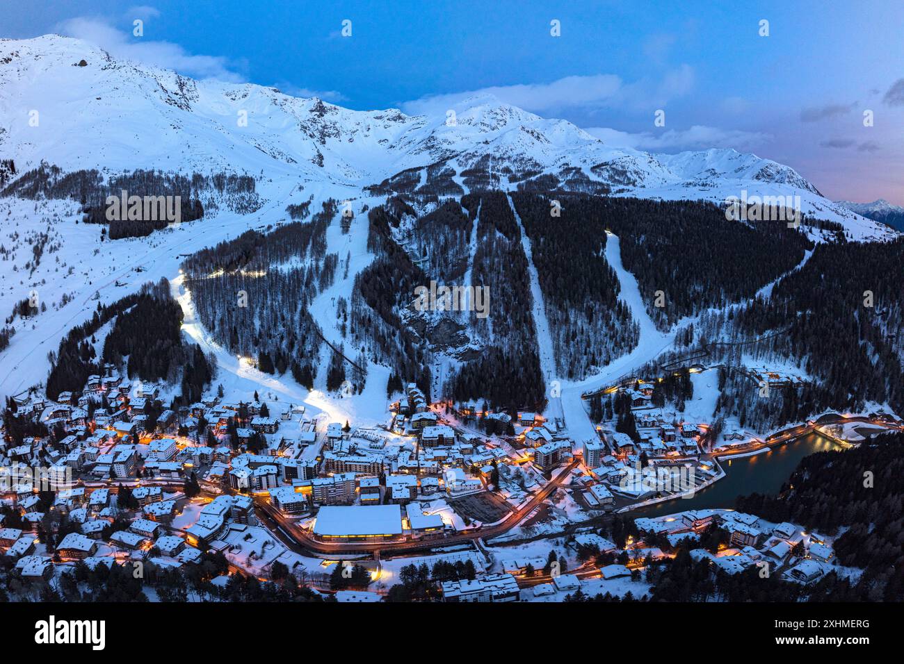 Aerial view of snowy ski slopes and Madesimo at night, Lombardy, Italy ...