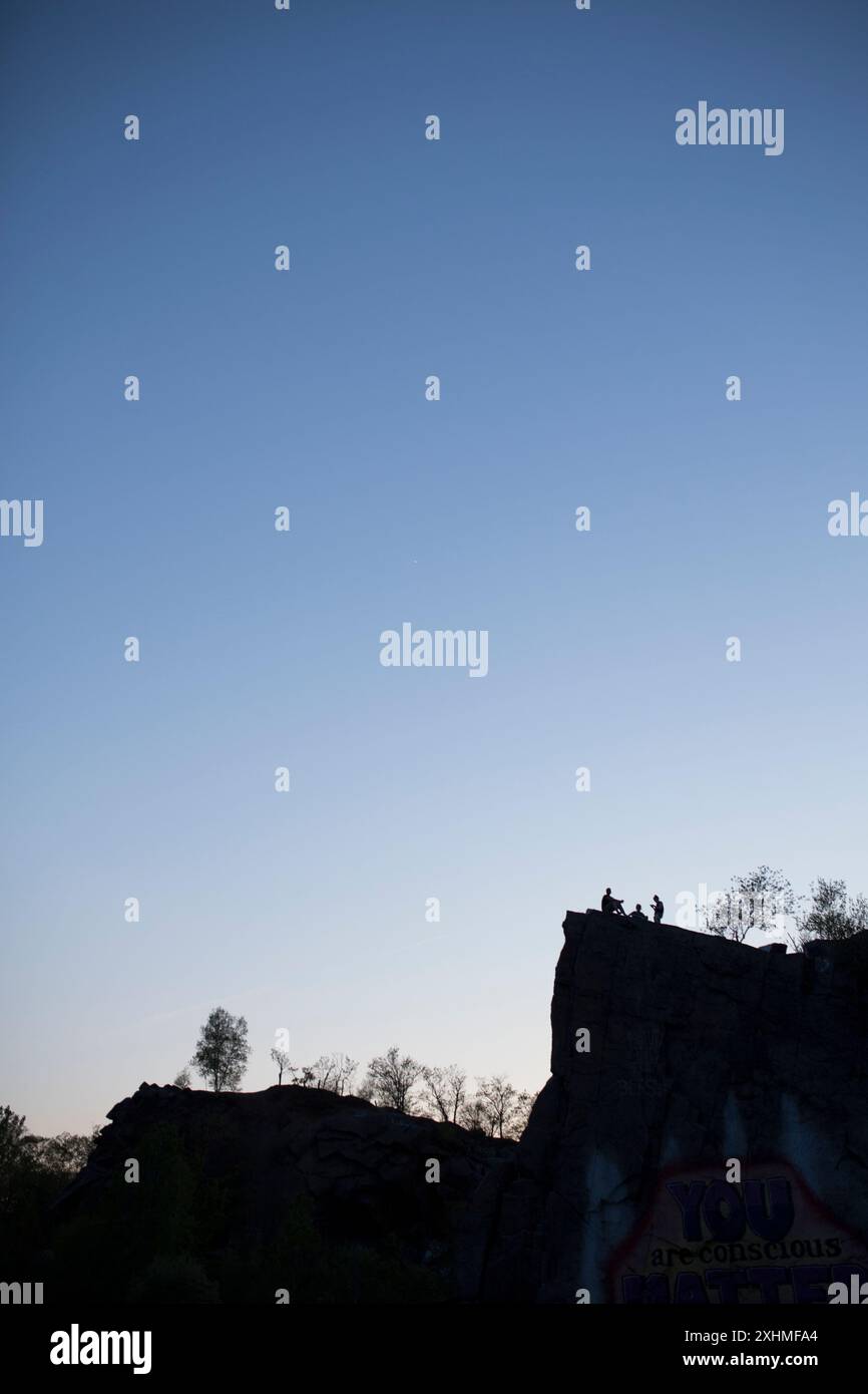 Silhouette of people on a rocky cliff during twilight Stock Photo - Alamy